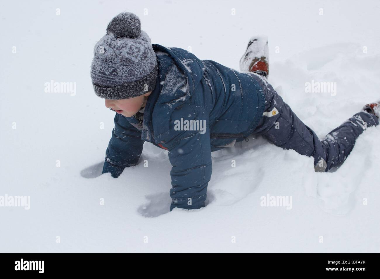 The boy fell on his stomach in the snow and stands on his feet Stock ...