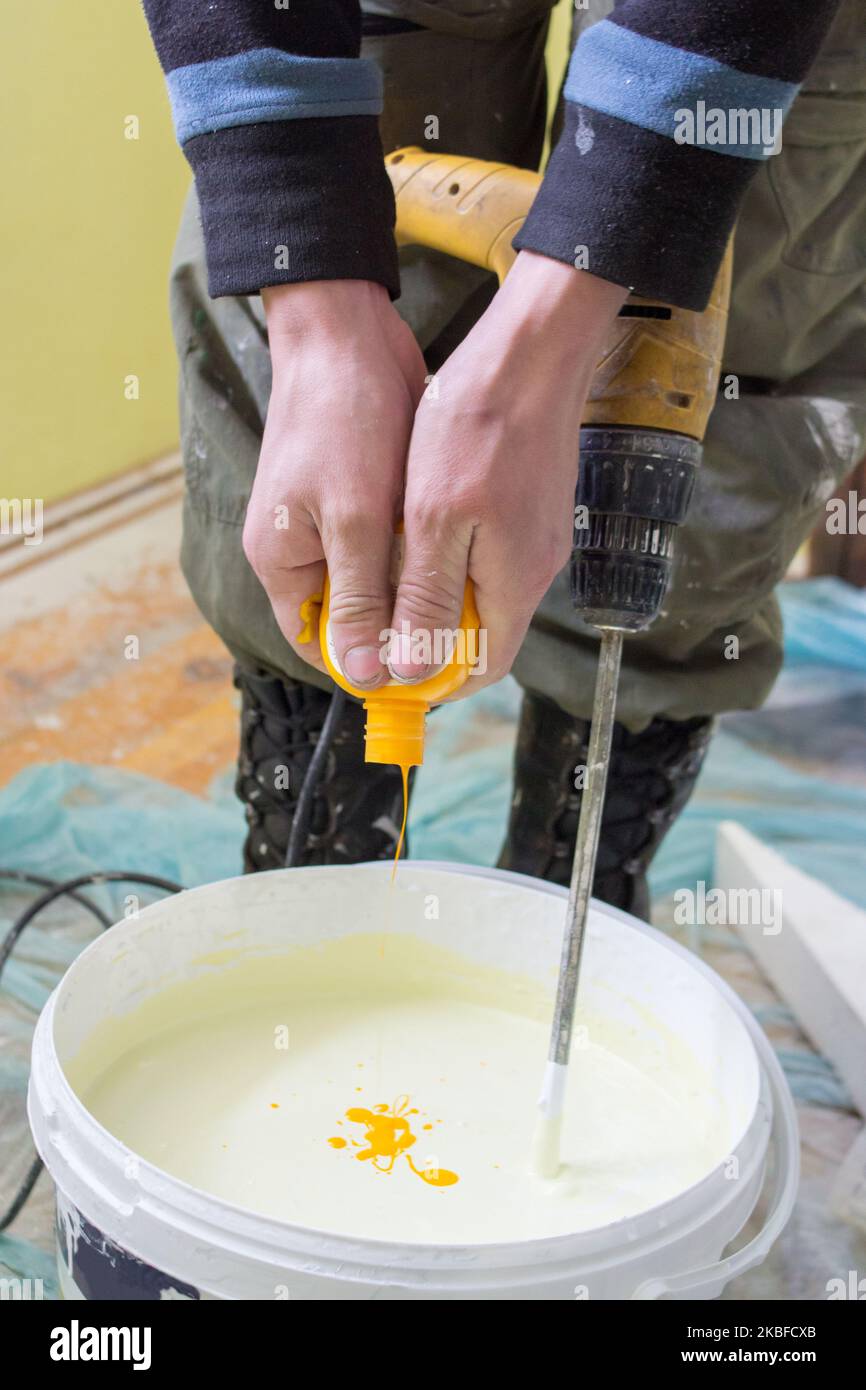 Man gives yellow coloring to white a paint for painting Stock Photo - Alamy