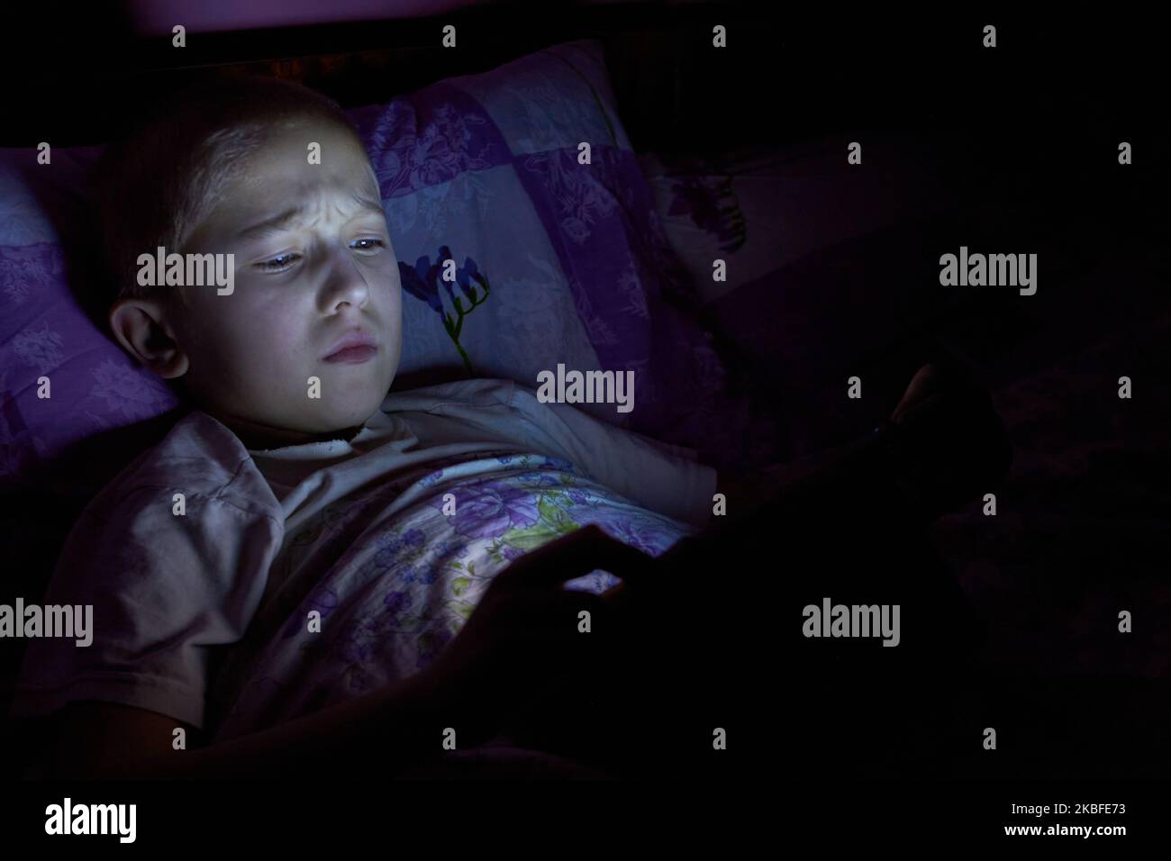 at night a little boy watching a scary movie on a tablet Stock Photo ...