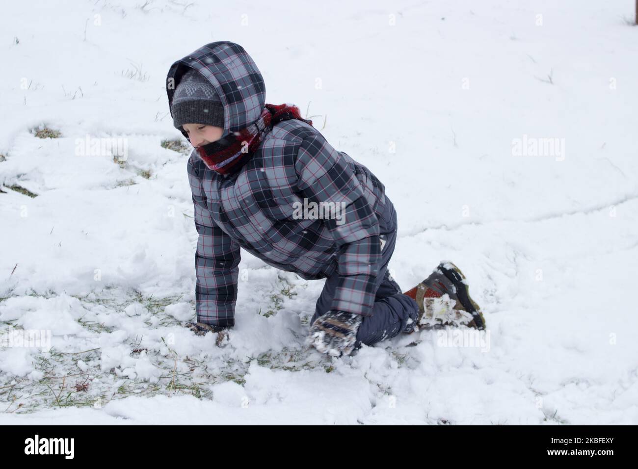 the boy crawls in the snow on the knees Stock Photo - Alamy