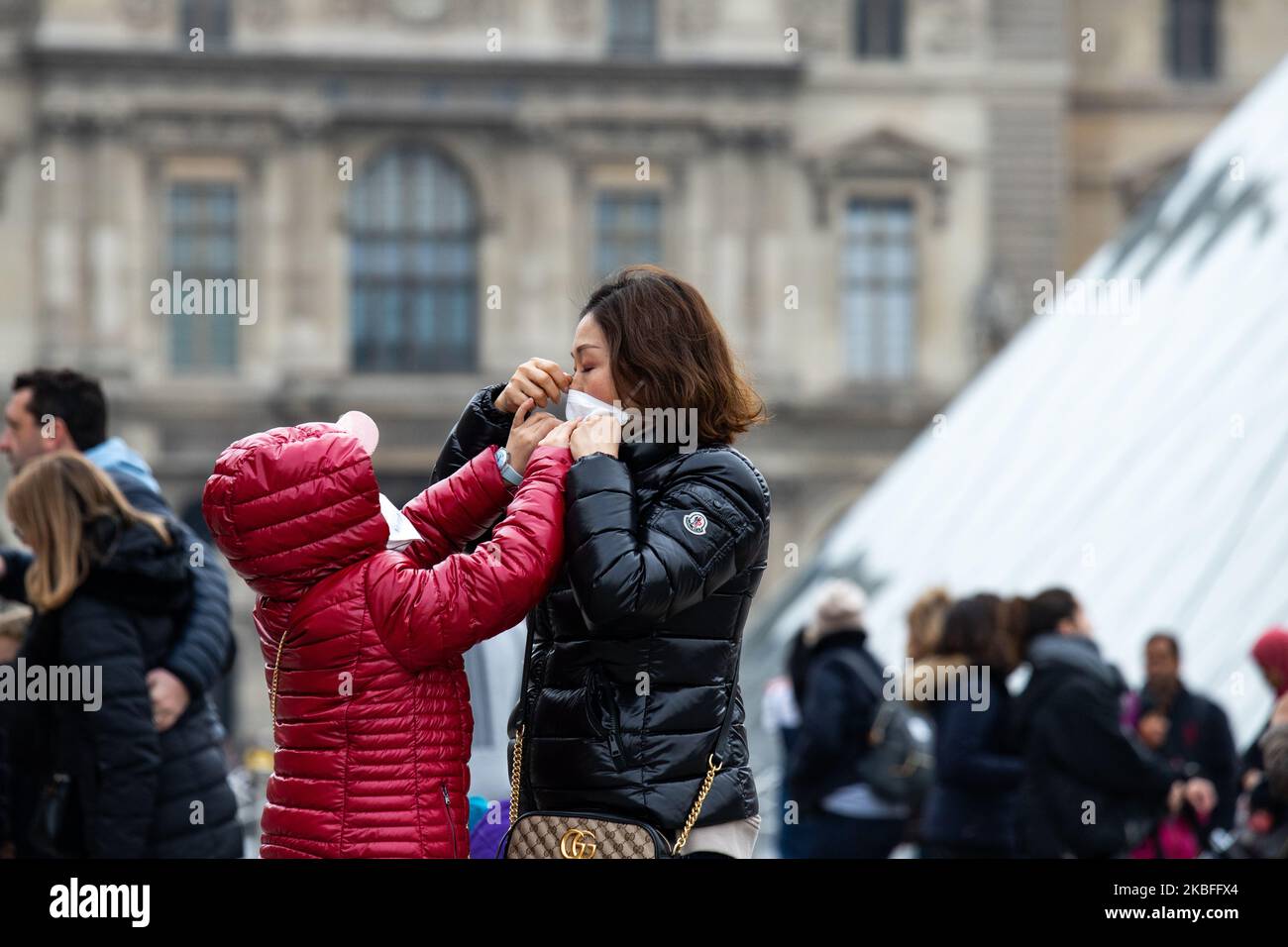 A girl helping her mother wearing her safety mask near the Louvre ...