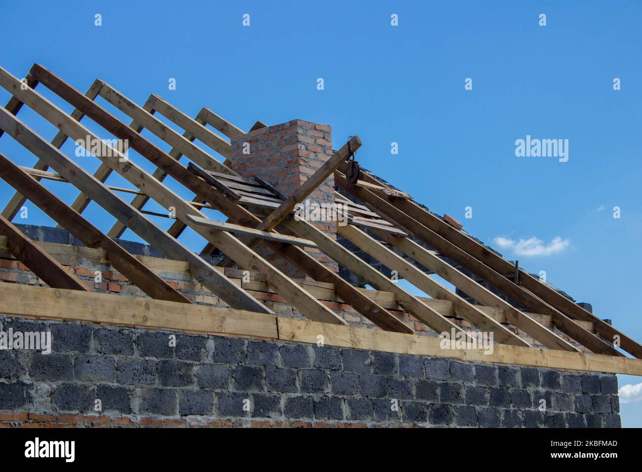 A new build roof with a wooden truss framework making an apex against a ...