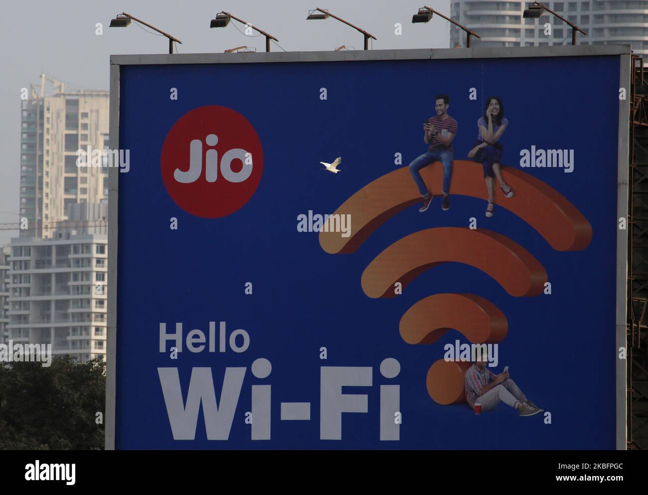 A bird flies past a billboard advertisement for Reliance Jio Infocomm ...