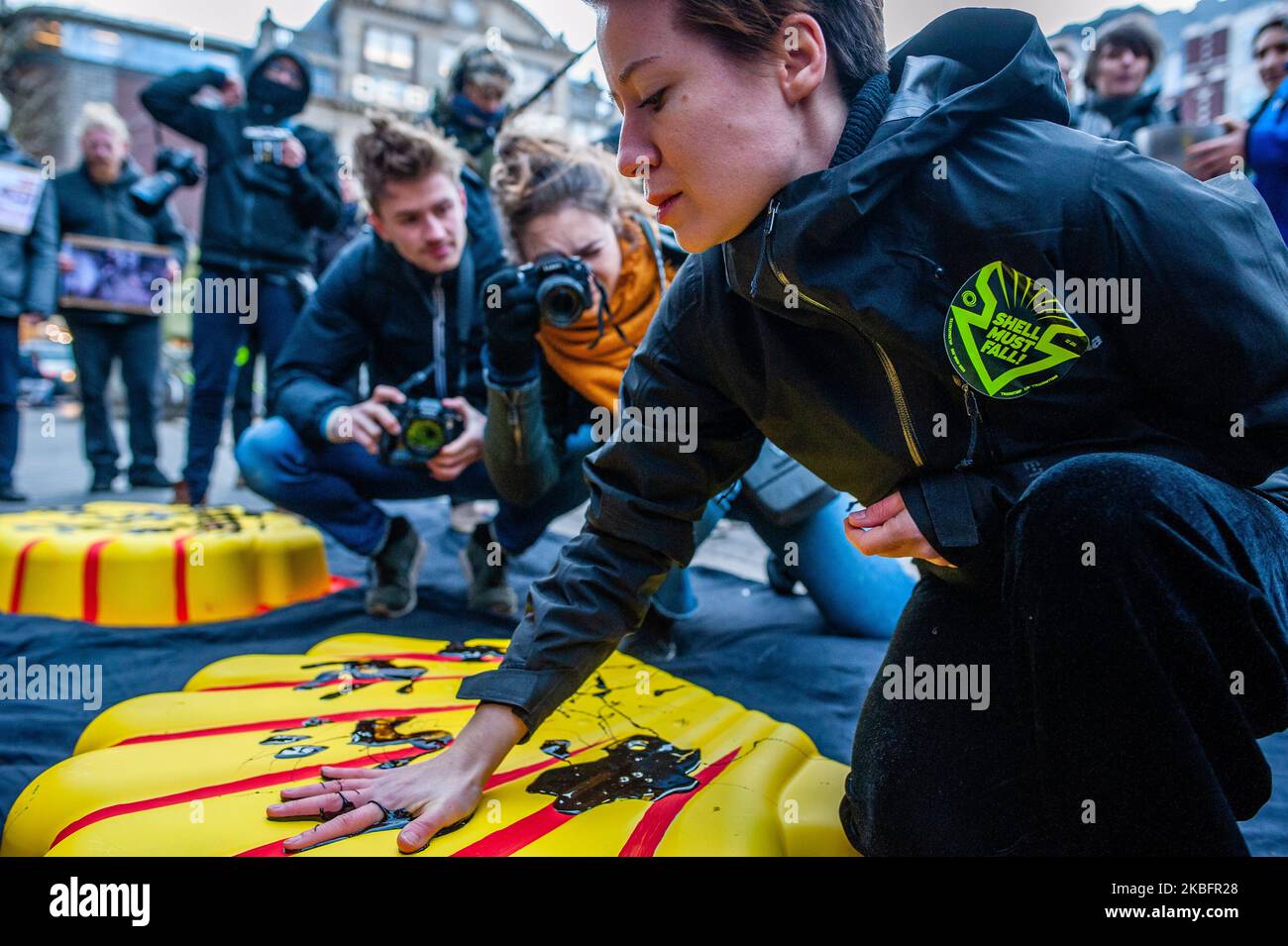 An activist is putting her hands stained with fake oil on a Shell logo ...