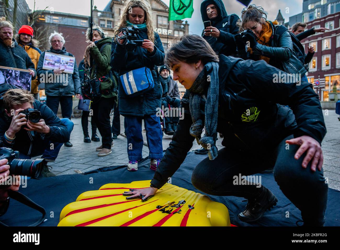 An activist is putting her hands stained with fake oil on a Shell logo ...