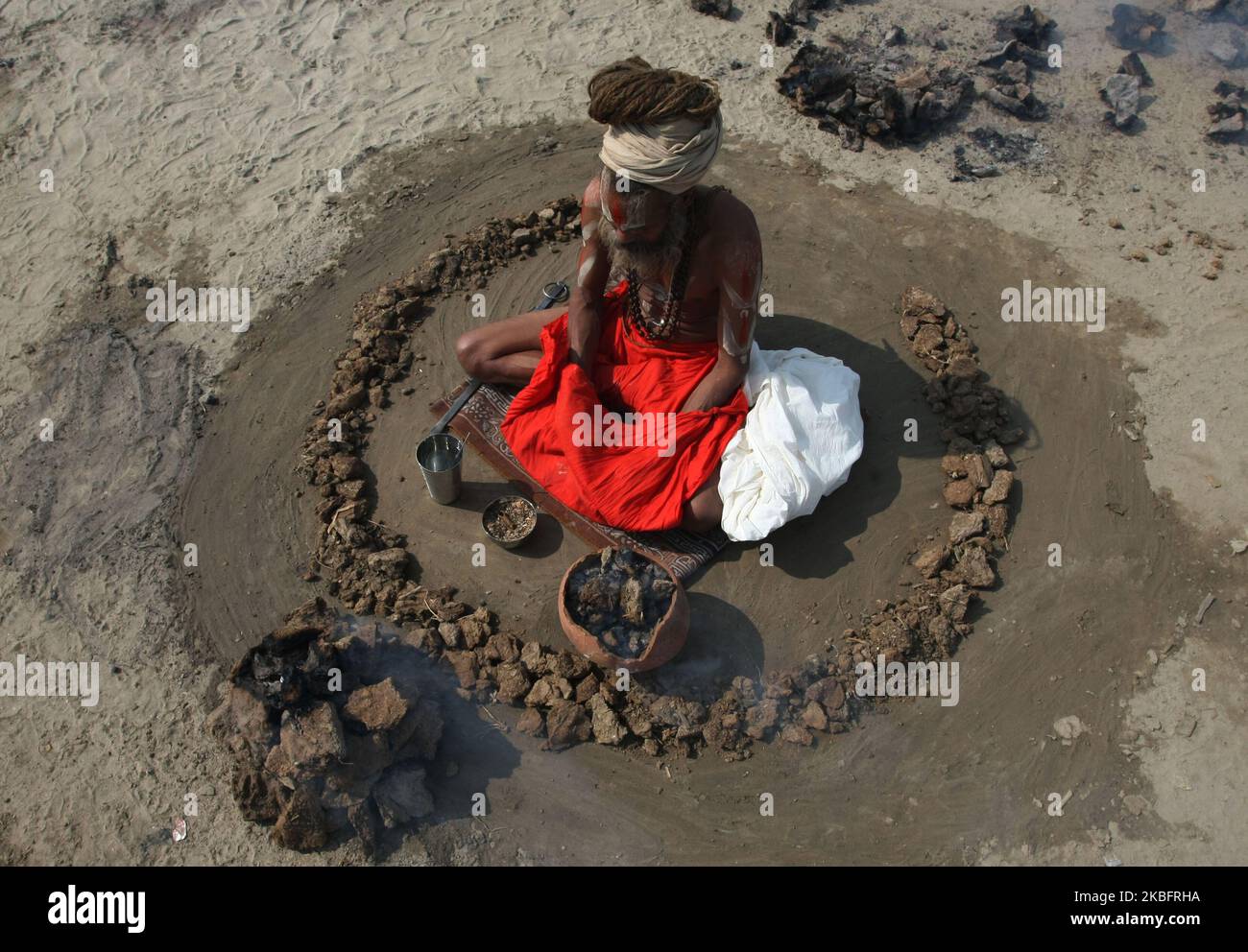 A devotee performs a ritual by burning dried cow dung cakes at sangam ...