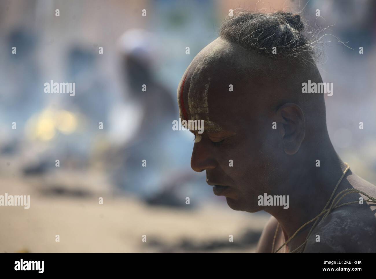 A devotee performs a ritual by burning dried cow dung cakes at sangam ...