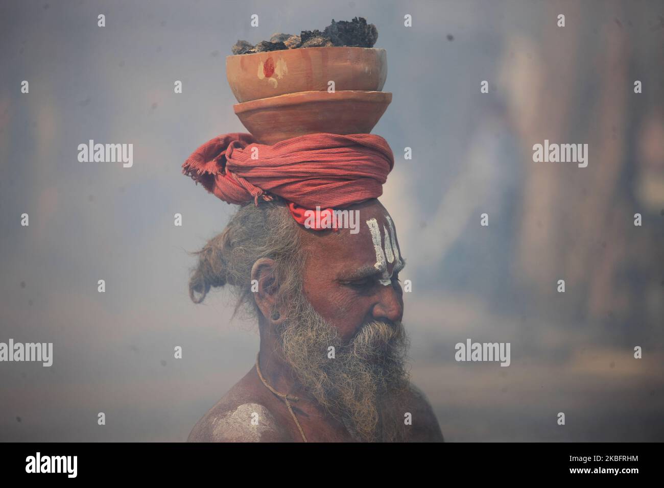 A devotee performs a ritual by burning dried cow dung cakes at sangam ...