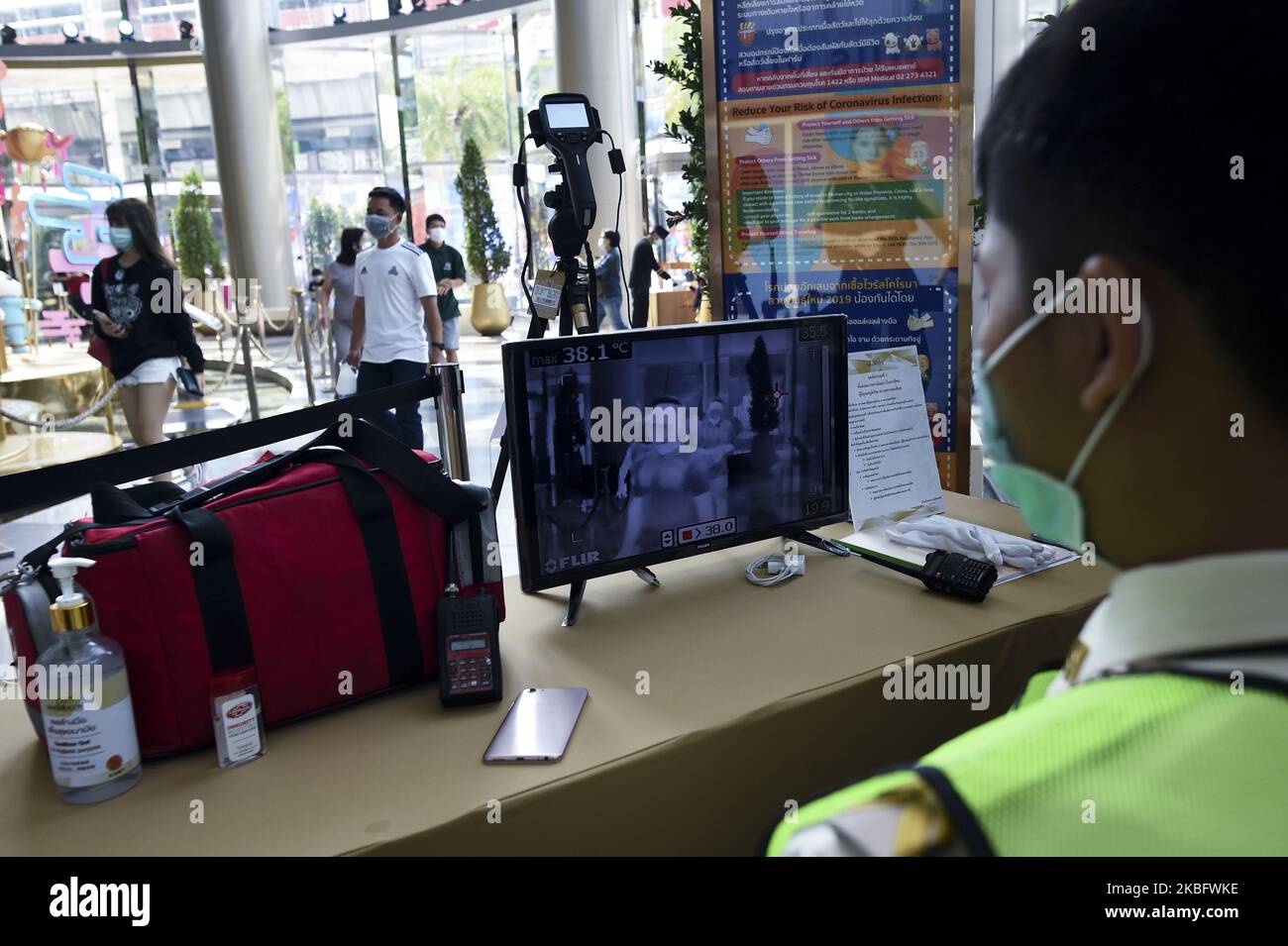 Security personnel use a thermal scanner to check people entering a ...