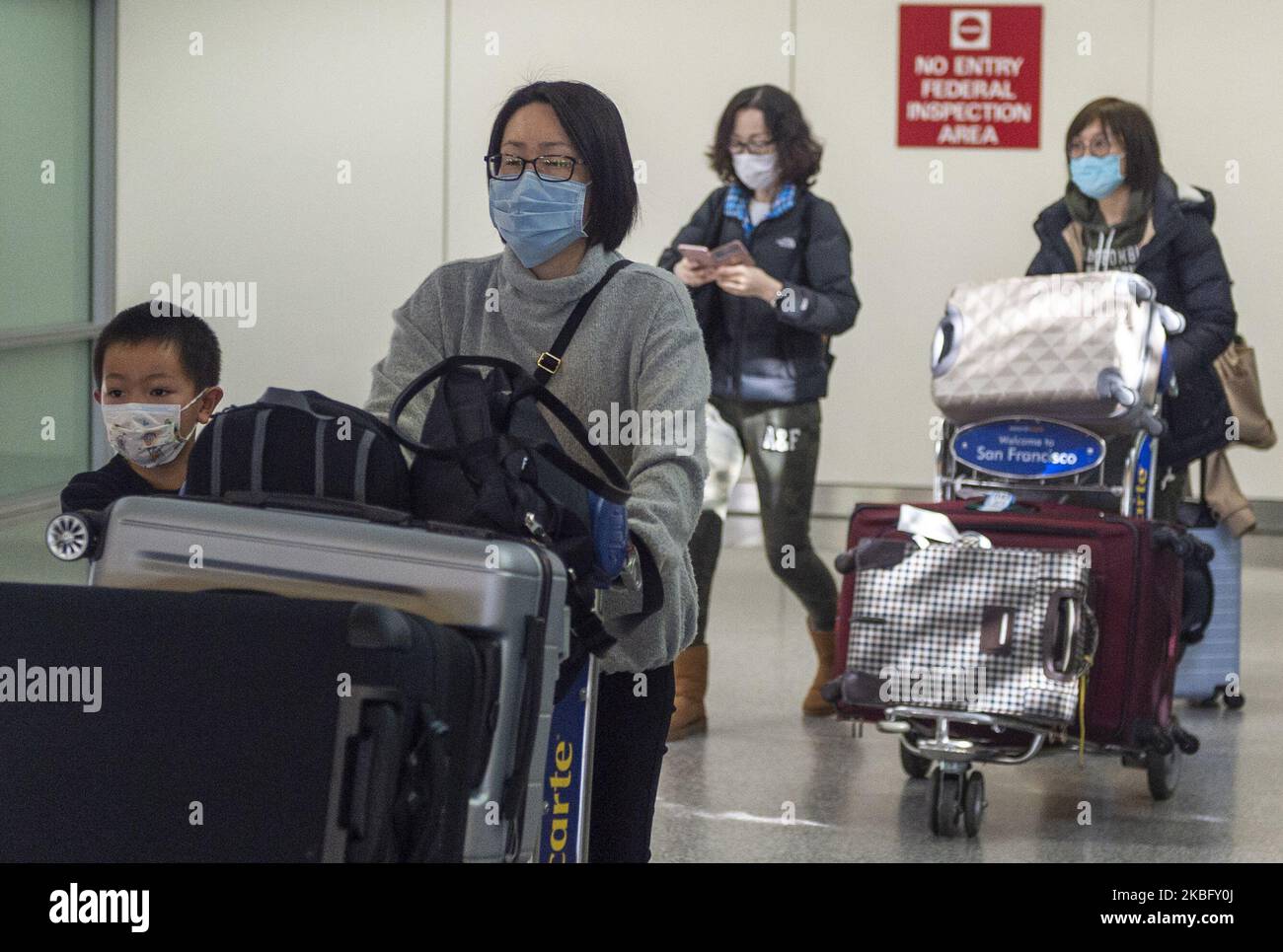 Airline passengers wearing face masks walk out of the international ...