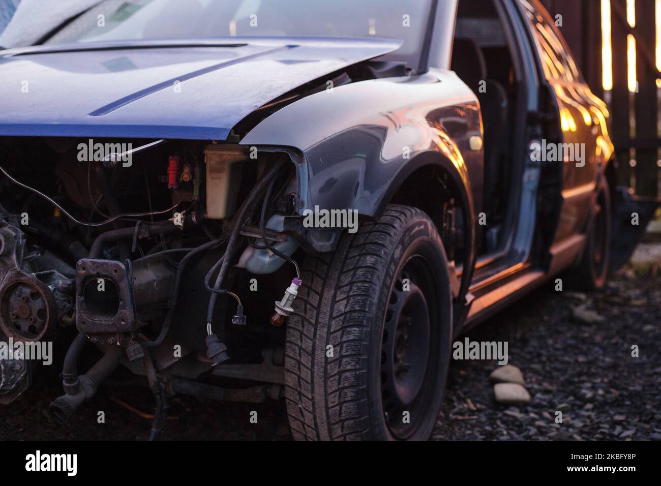 Damaged car after accident with uncovered engine pictured during sunset ...