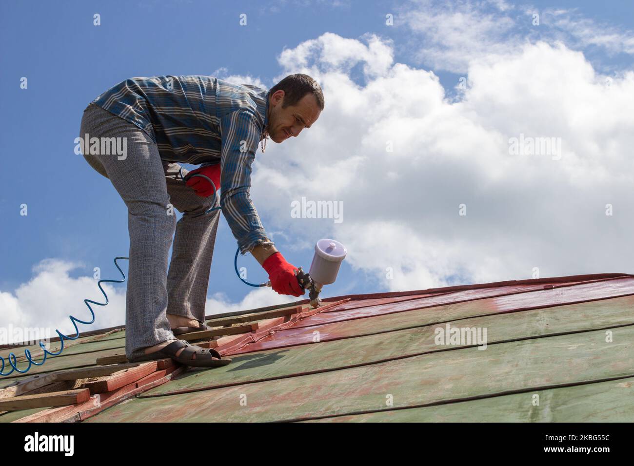 spray red color to paint the roof of a building Stock Photo - Alamy