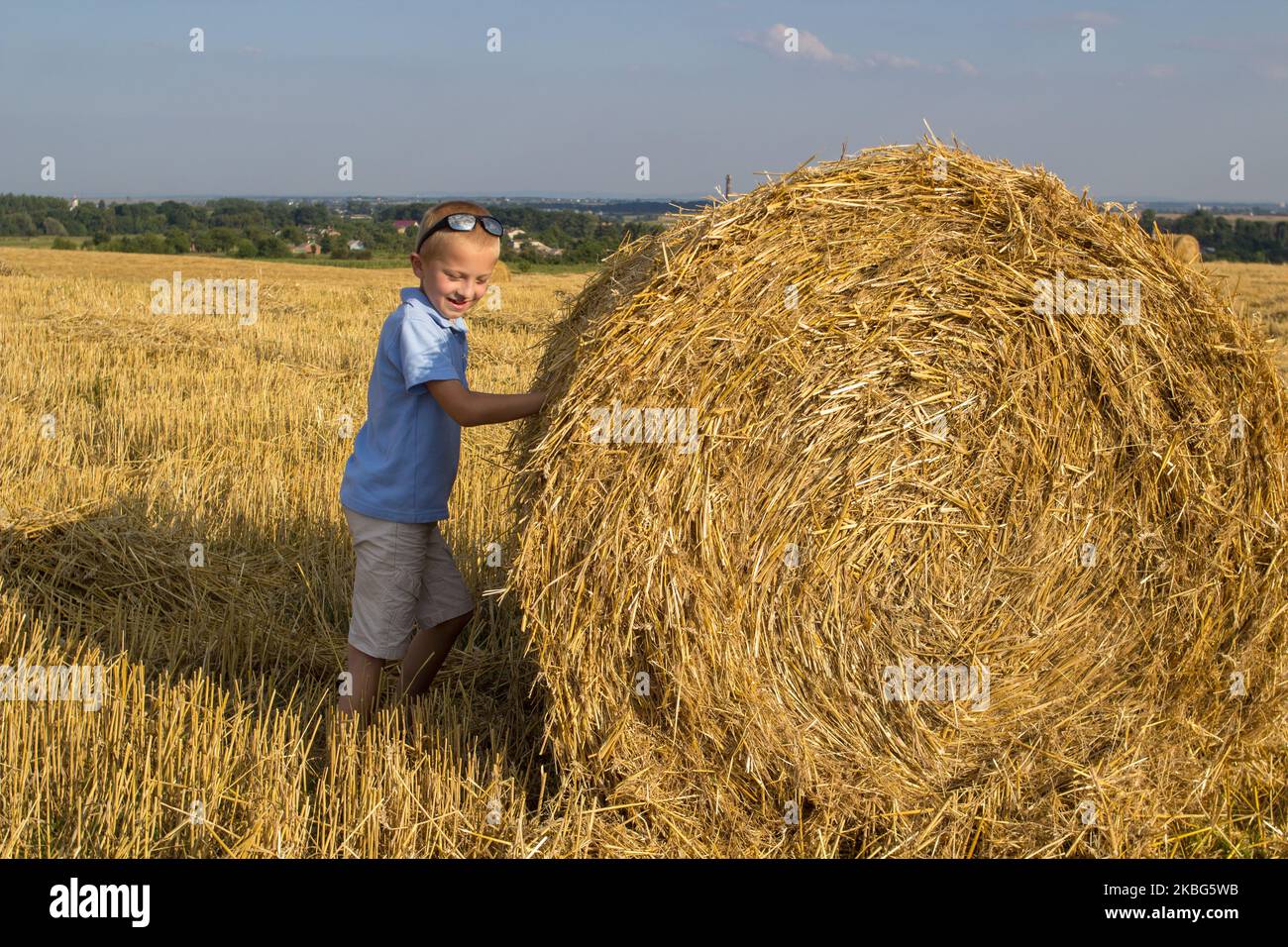 Adorable little kid standing next to hay bale, Active outdoors leisure ...