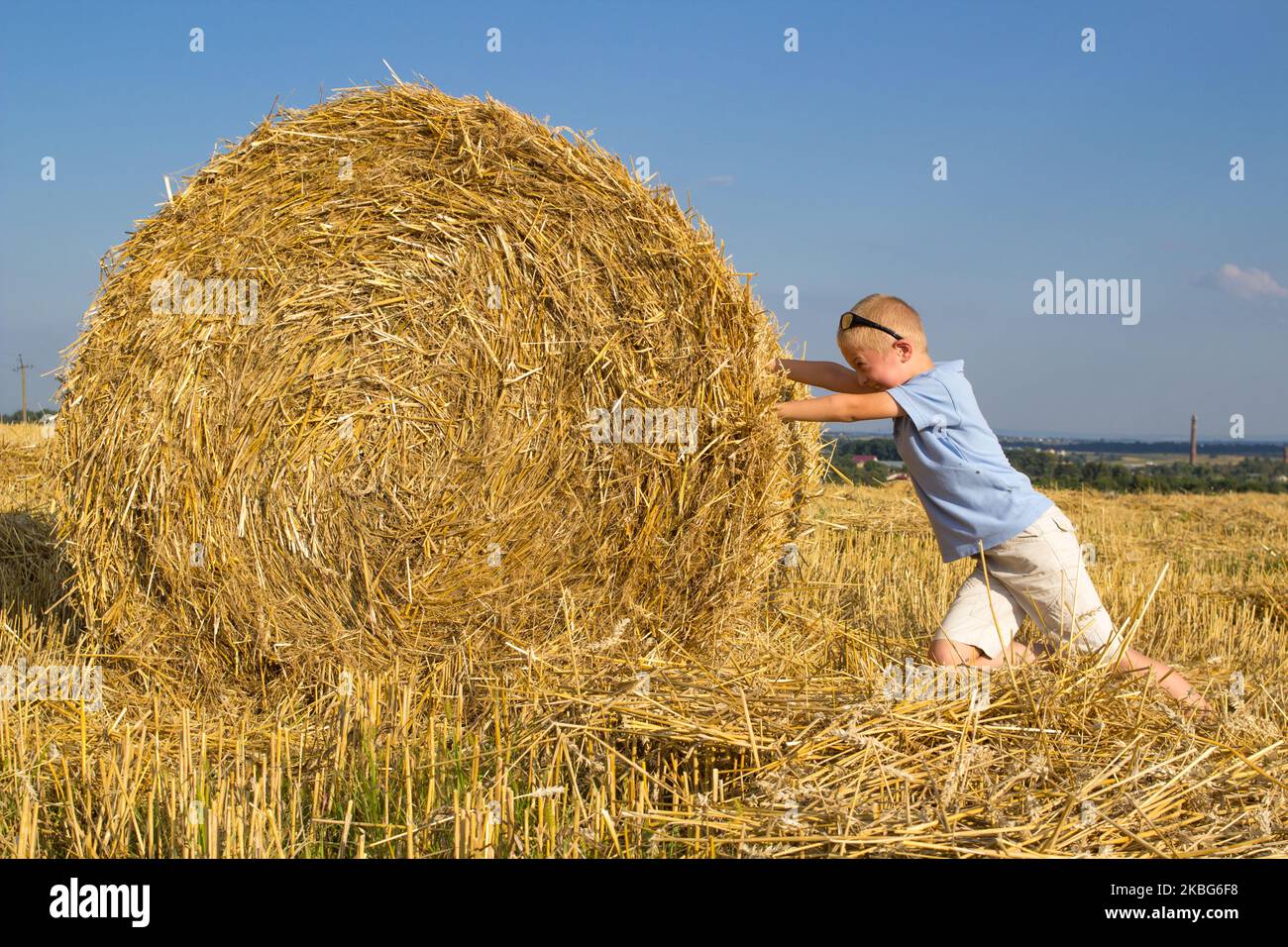 Boy boy's emotions pitch a big bale of hay in the field Stock Photo - Alamy