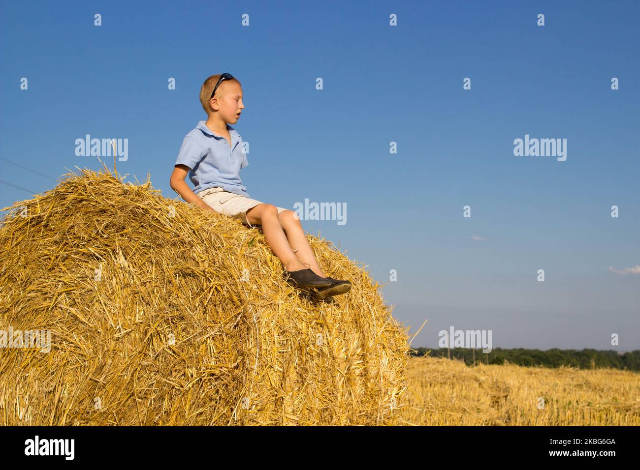 The boy sat with his eyes closed on a bale of hay Stock Photo - Alamy