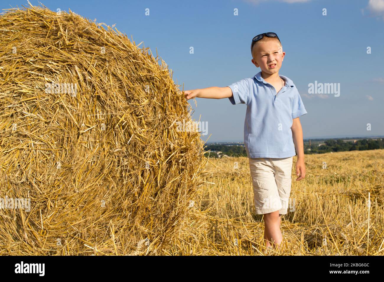 The boy stood next to a round of a bale of hay Stock Photo - Alamy