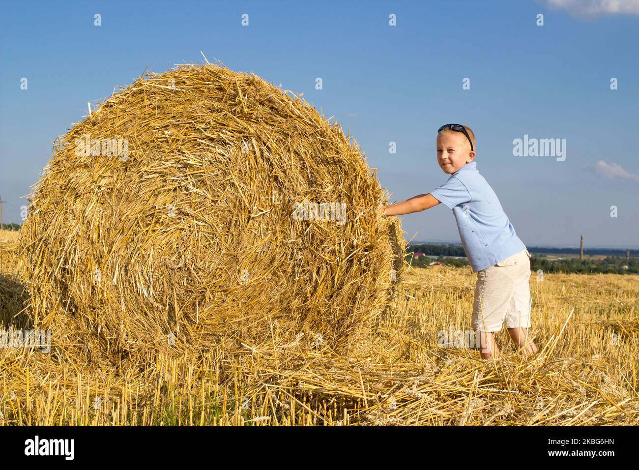 The boy is holding a bale of hay in the field Stock Photo - Alamy