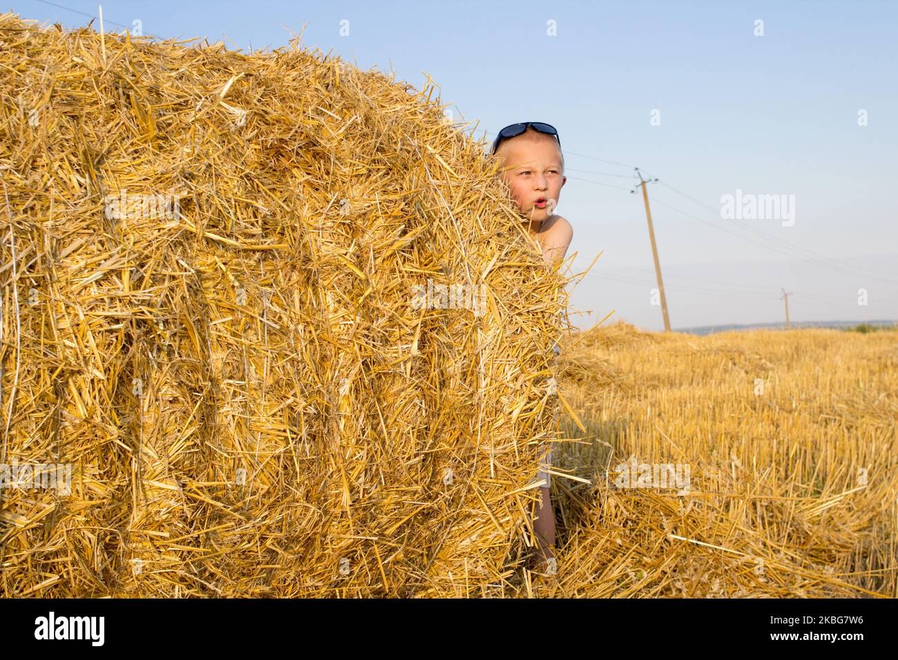 The boy is hiding behind a bale of hay in the field Stock Photo - Alamy