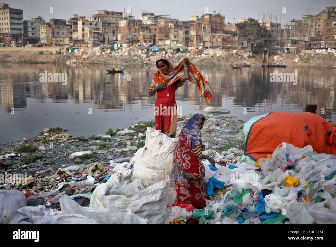 Women collect used polythene from garbage for recycling besides the ...