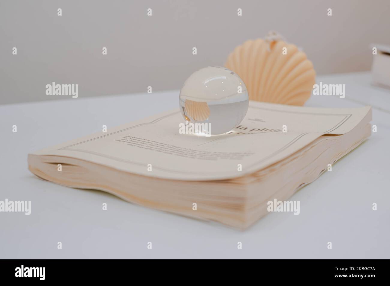 Rounded glass decoration above a book in white table with blurred ...