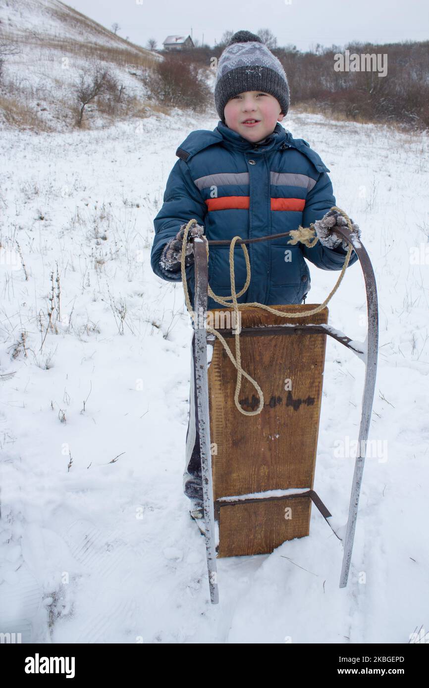 The boy in a cold winter day, a walk in the Park, holding the sled ...