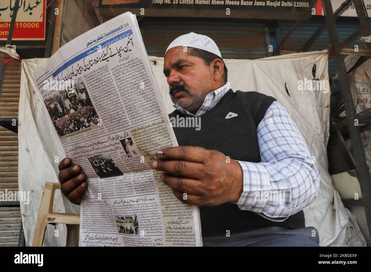 A muslim man reads a newspaper after casting his vote in the ...