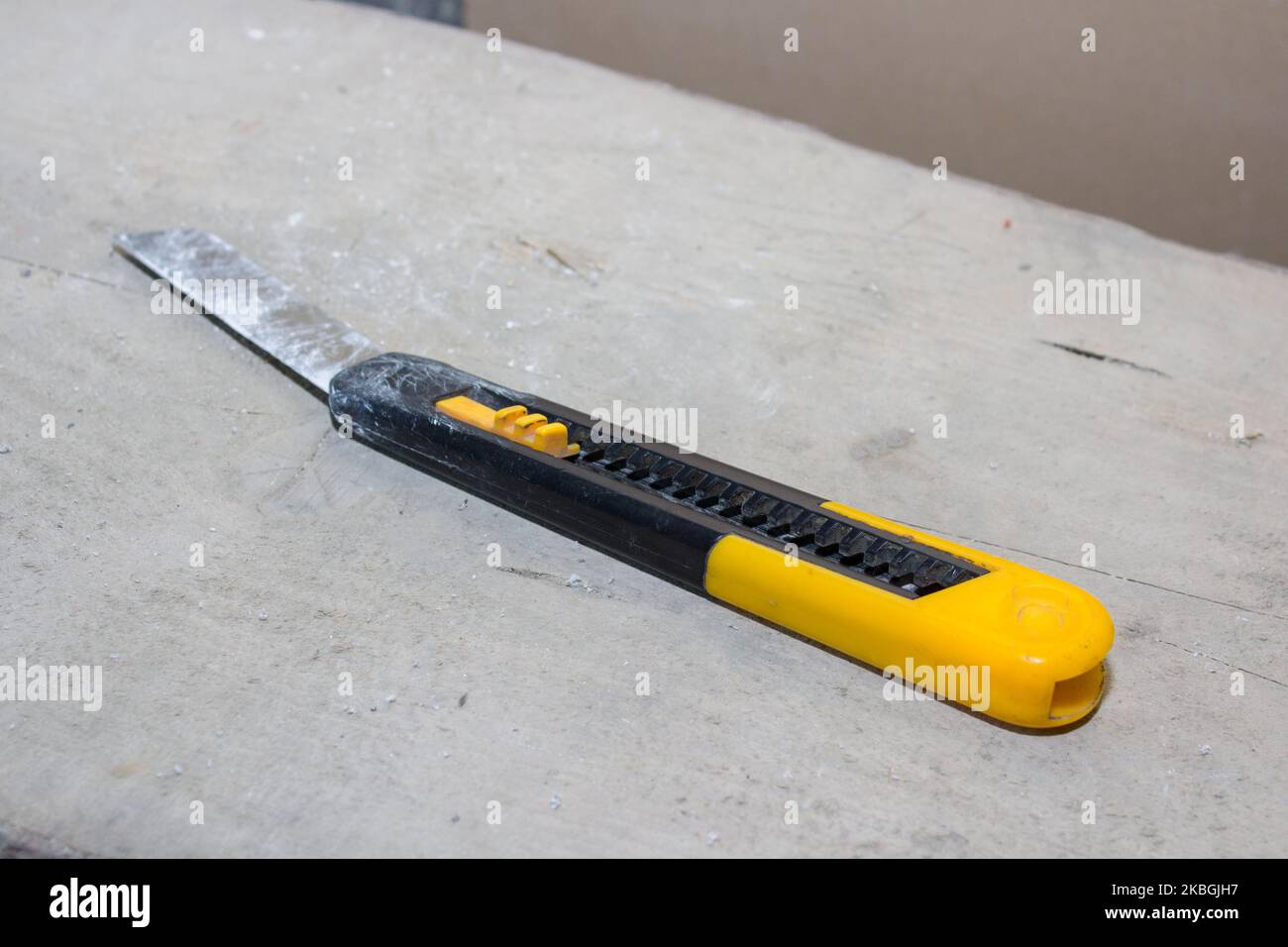 Yellow stationery knife lying on a dirty wooden board Stock Photo - Alamy