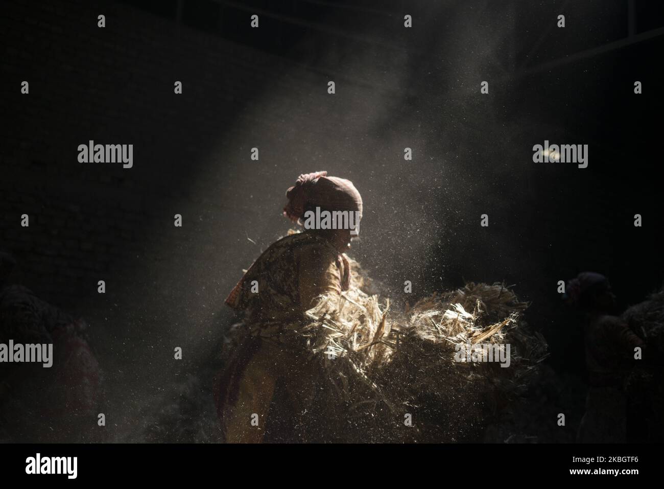 Women workers working inside a jute mill while sun rays coming from the ...