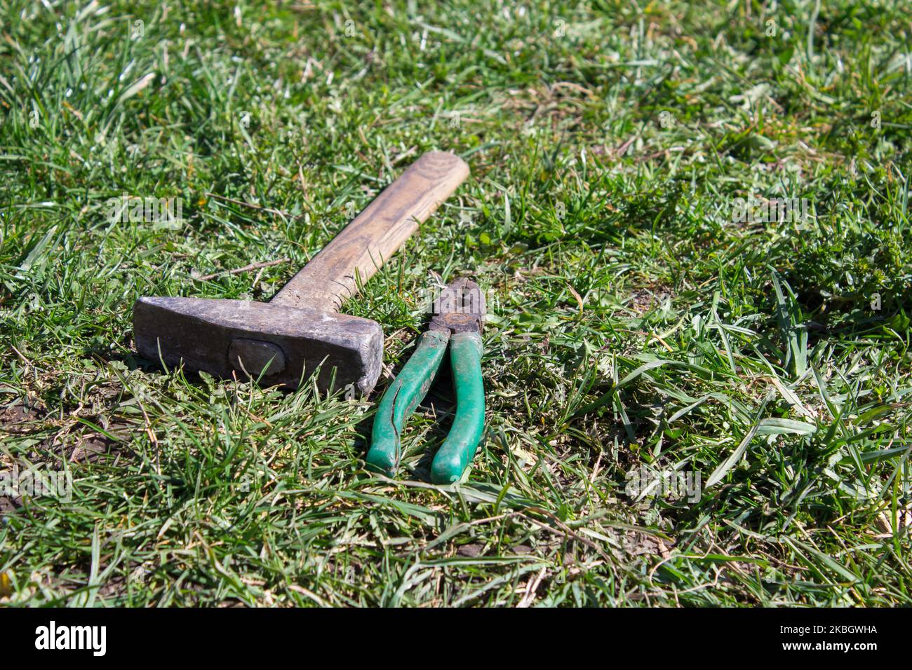 tools lying on the grass hammer and pliers Stock Photo - Alamy