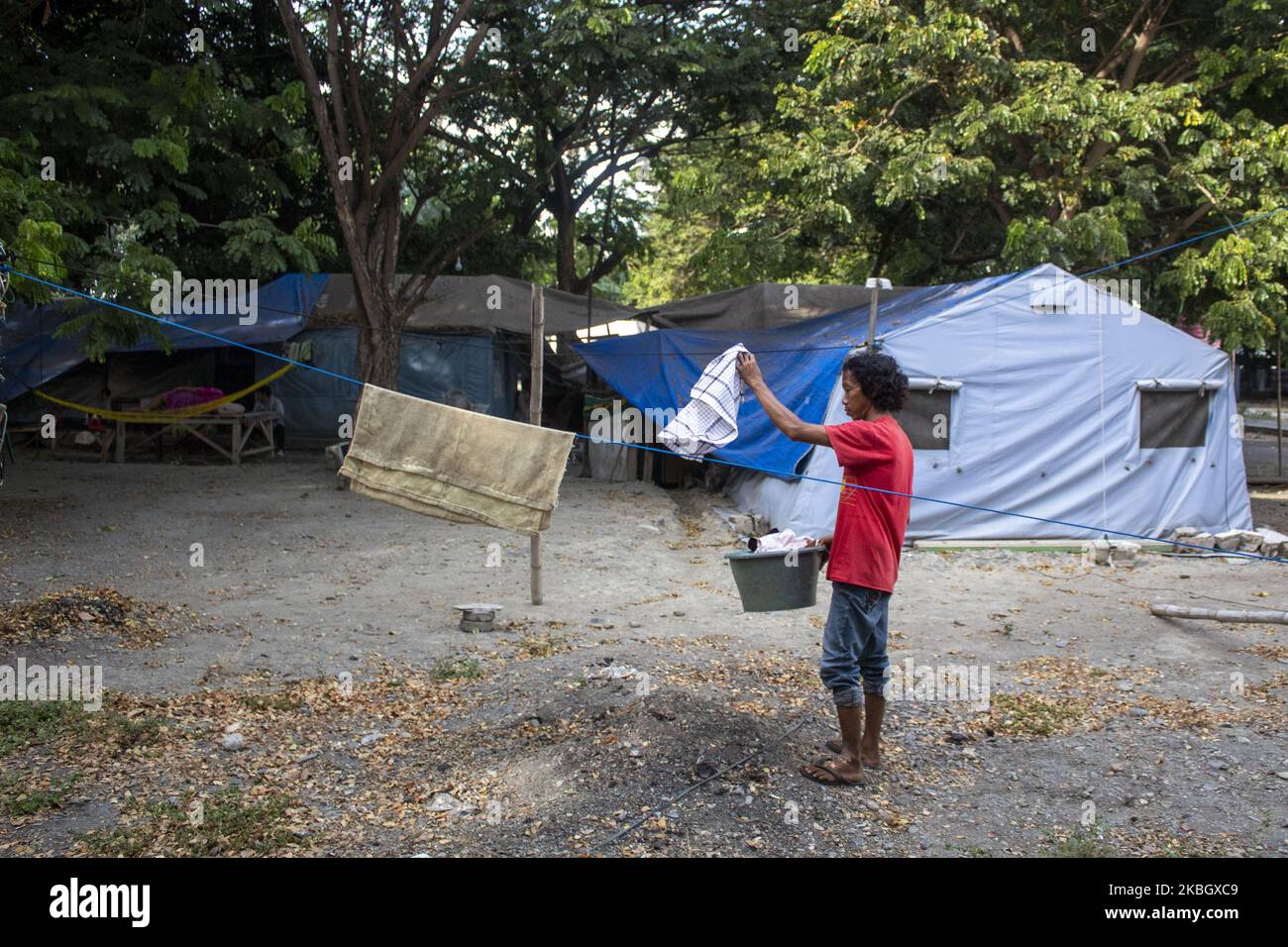 A disaster survivor picks up clothes from a clothesline near his ...