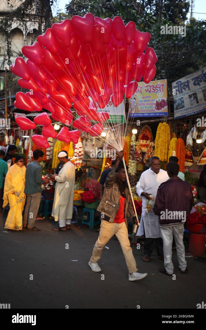 A vendor walks as he holds heart shaped balloons to sell before the day ...