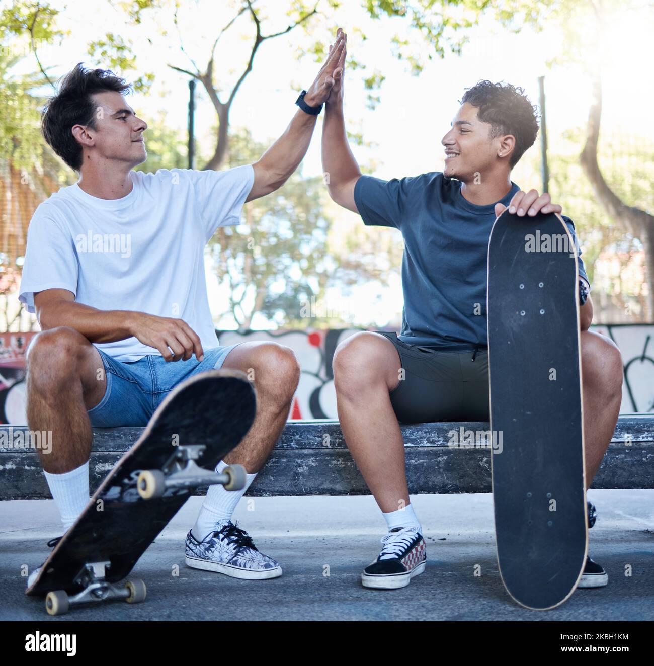 High five, skateboard and skater friends at city skatepark, young men ...