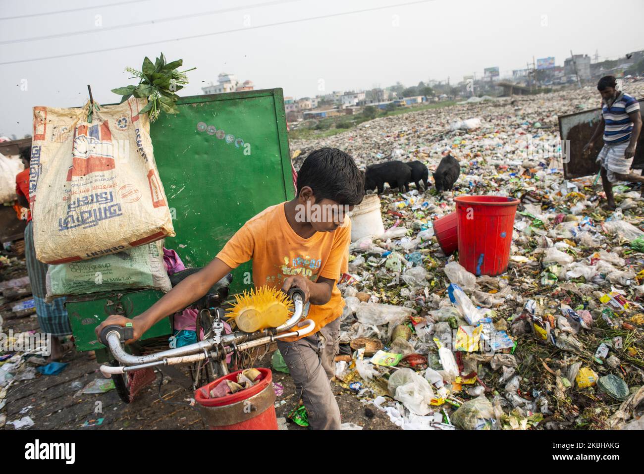 An underage boy pulling back his cart out just after dumping the trash ...