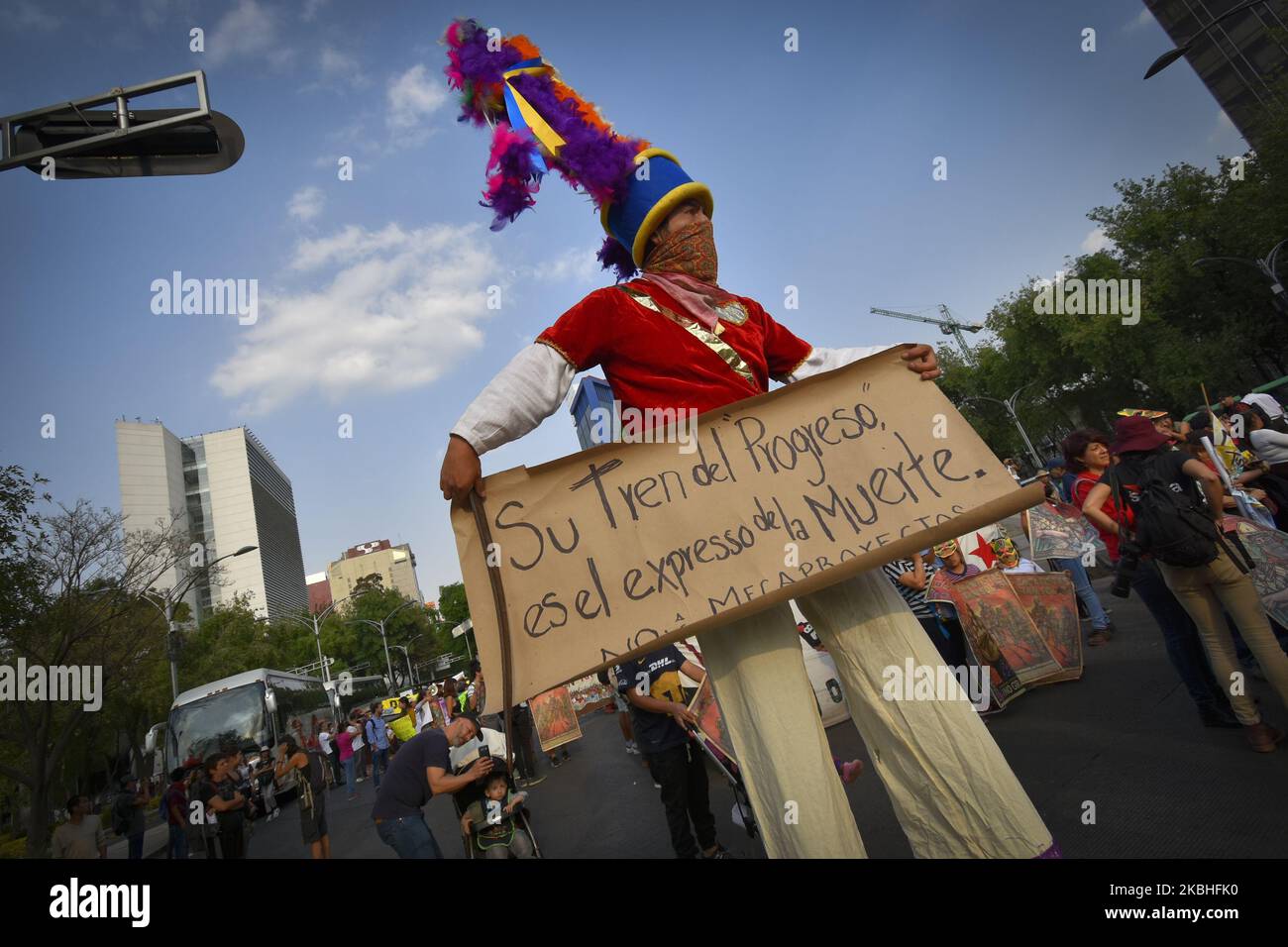 A demonstrators with stilts holds a sign against Maya Train during a ...