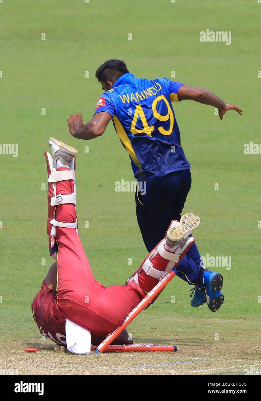 West Indies cricketer Darren Bravo crashes in to the stumps as he is ...