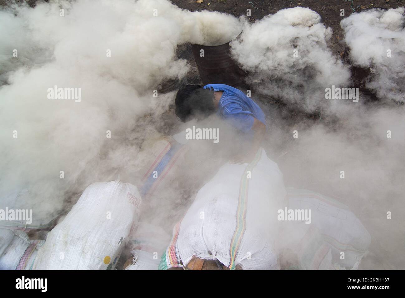 Worker put coconut shell into burning drums for charcoal making in the ...