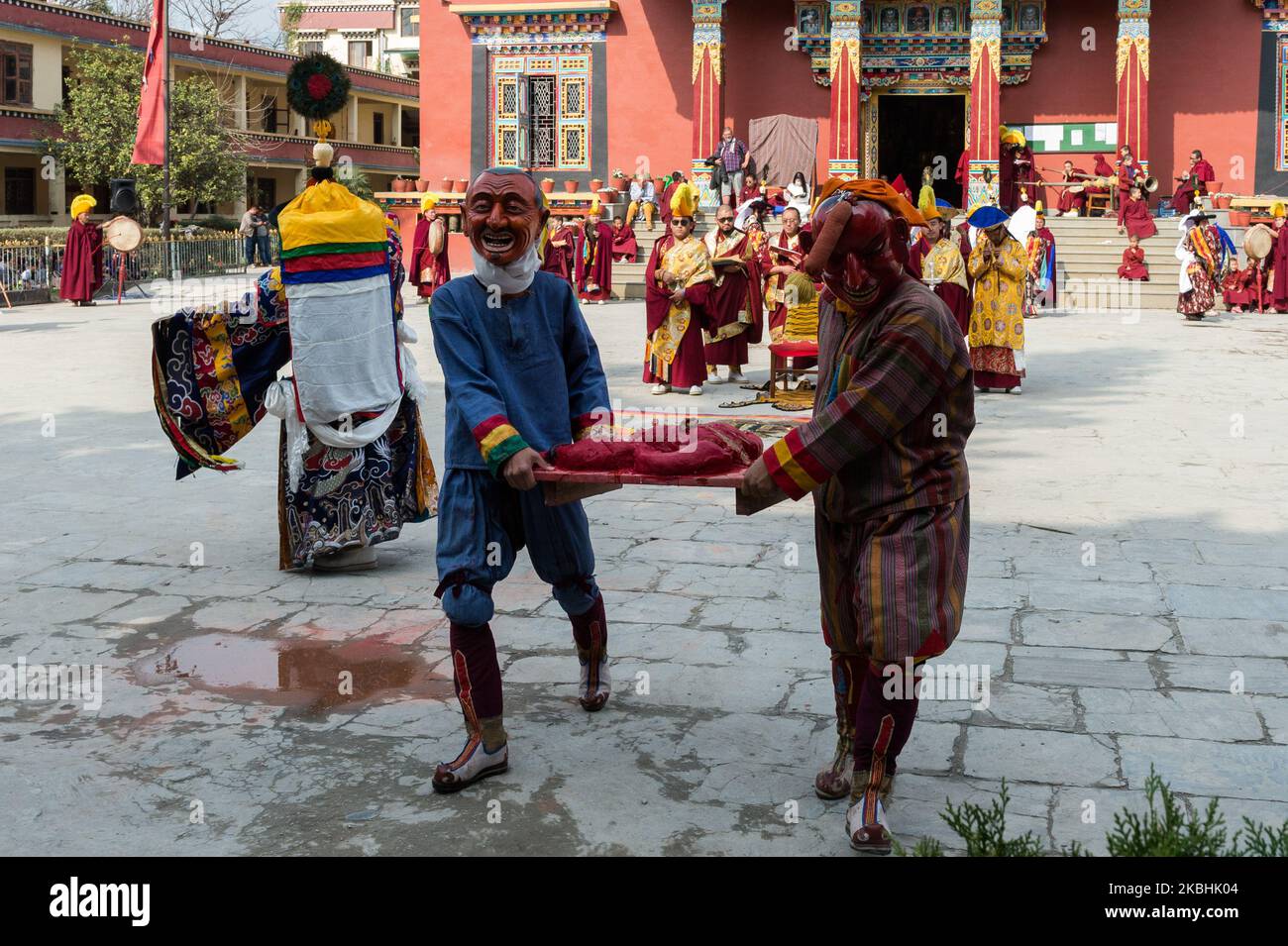 Tibetan monks wearing achara (joker) masks carry the effigy of 'linga ...