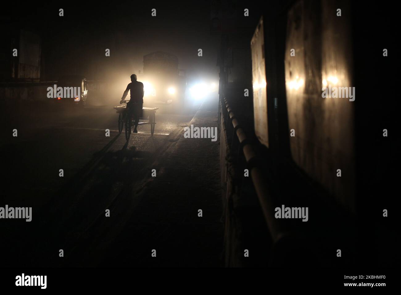 A Van puller passes in a dusty road at night in Dhaka, Bangladesh on ...