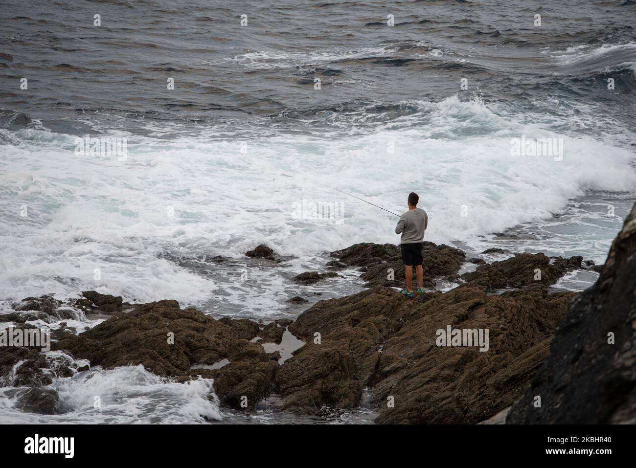 fisherman casting the rod from the rocks Stock Photo - Alamy