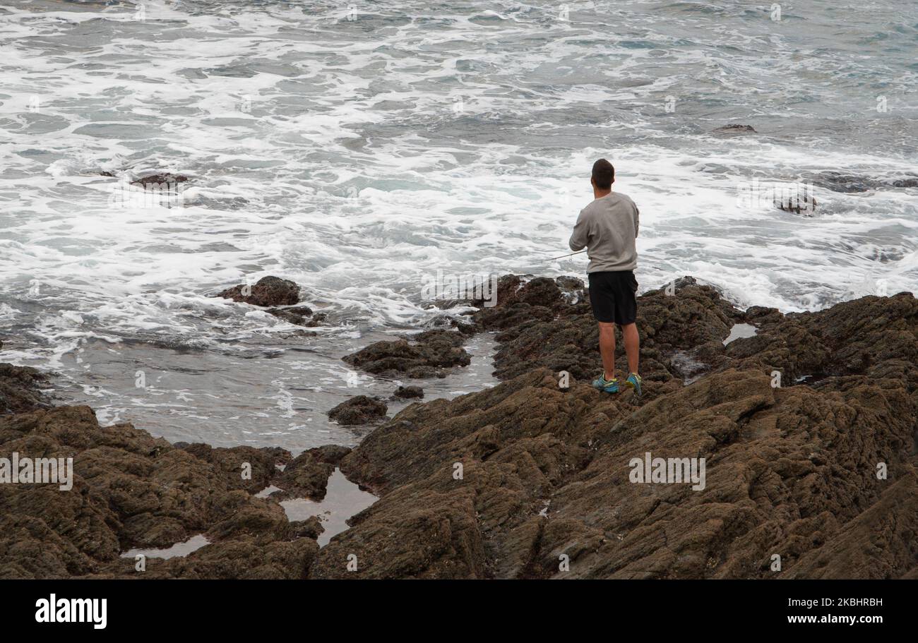 fisherman casting the rod from the rocks Stock Photo - Alamy