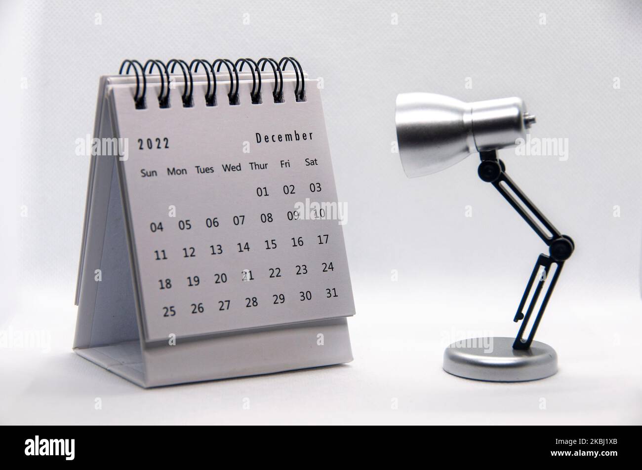 December 2022 white desk calendar on white background with table lamp ...