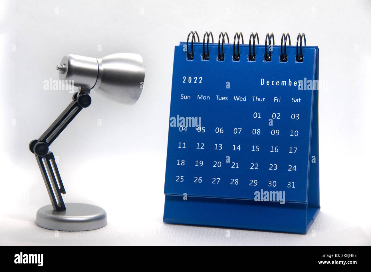 December 2022 blue desk calendar on white background with table lamp ...