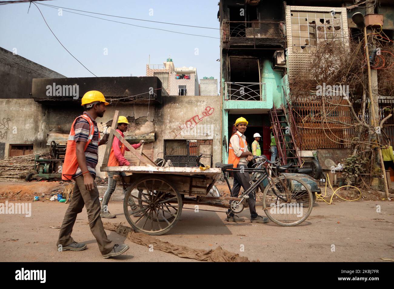 Workers walk besides burnt building after it was set on fire by a mob ...