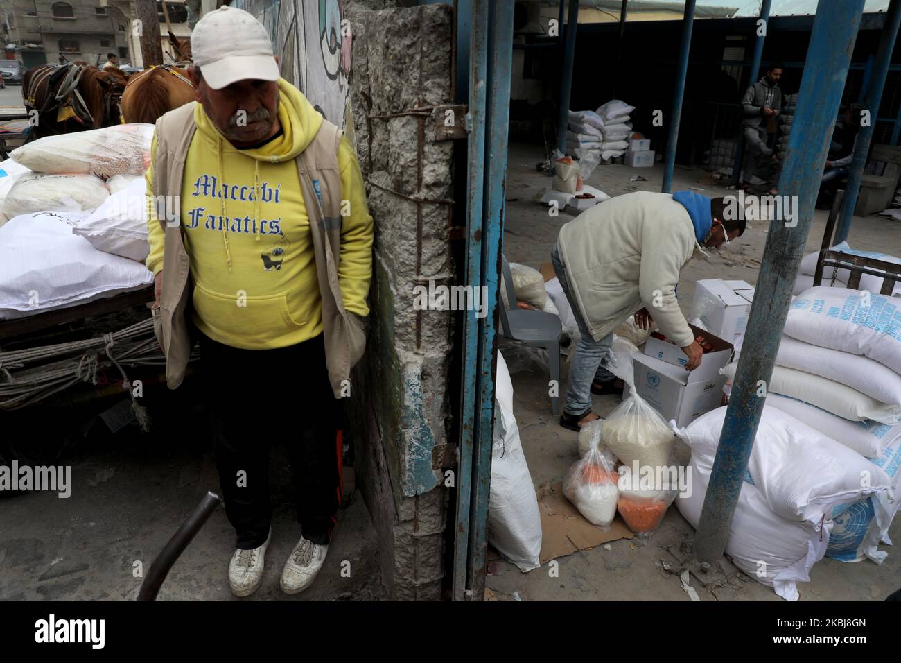 Palestinians carry sacks of flour as people receive food aid from a ...