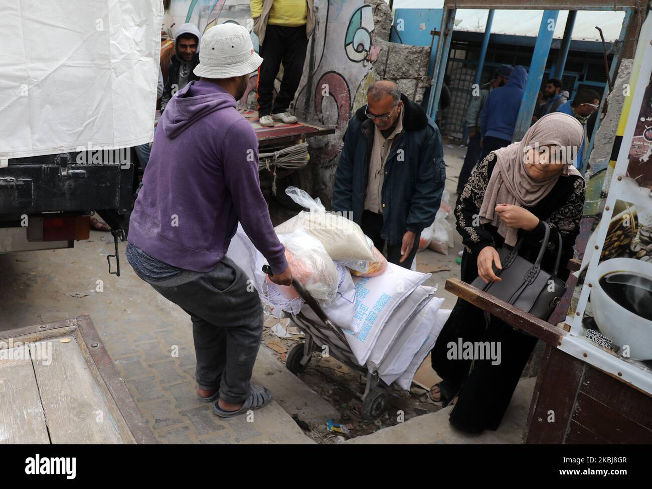Palestinians carry sacks of flour as people receive food aid from a ...