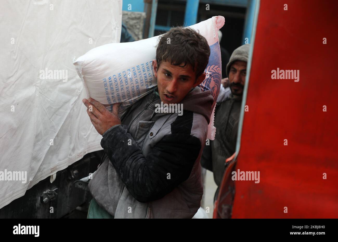 Palestinians carry sacks of flour as people receive food aid from a ...
