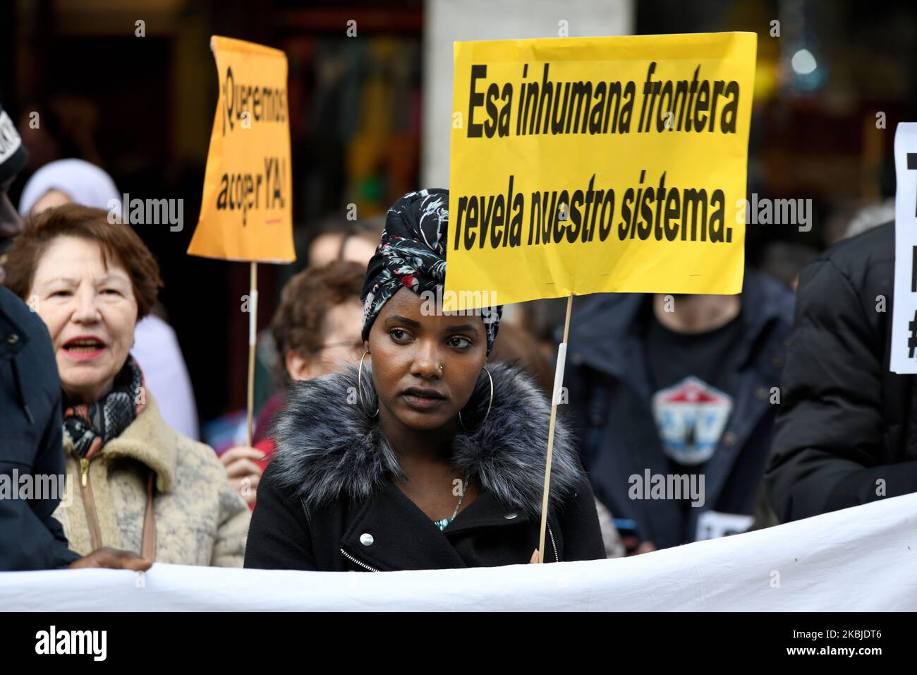 A woman holds up a placard reading 'That inhuman frontier, reveals our ...