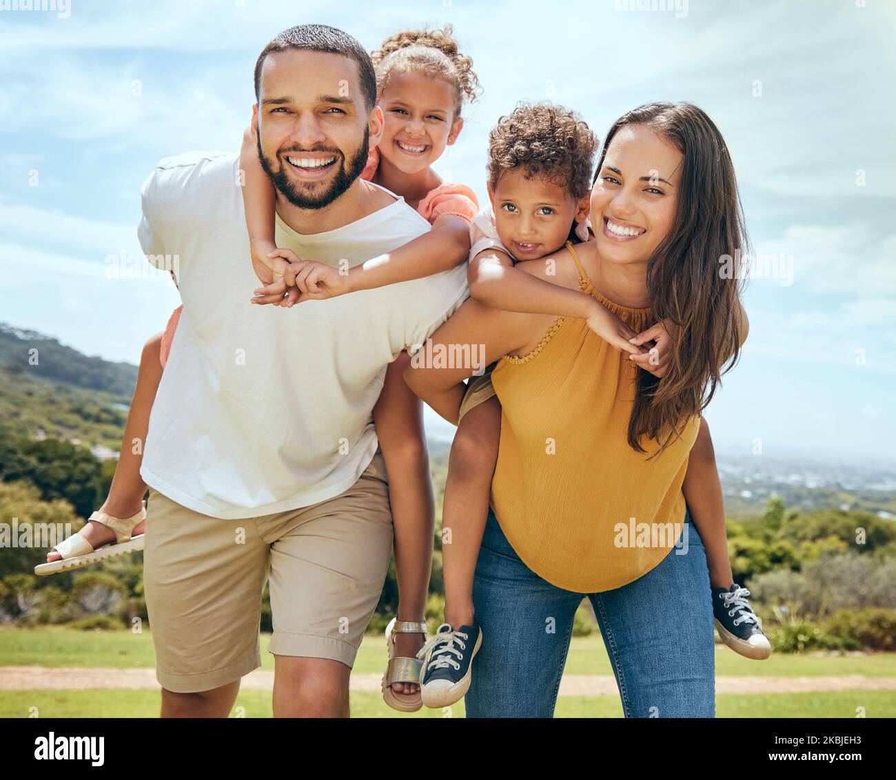 Happy family, mother and father with children on back in a nature park ...