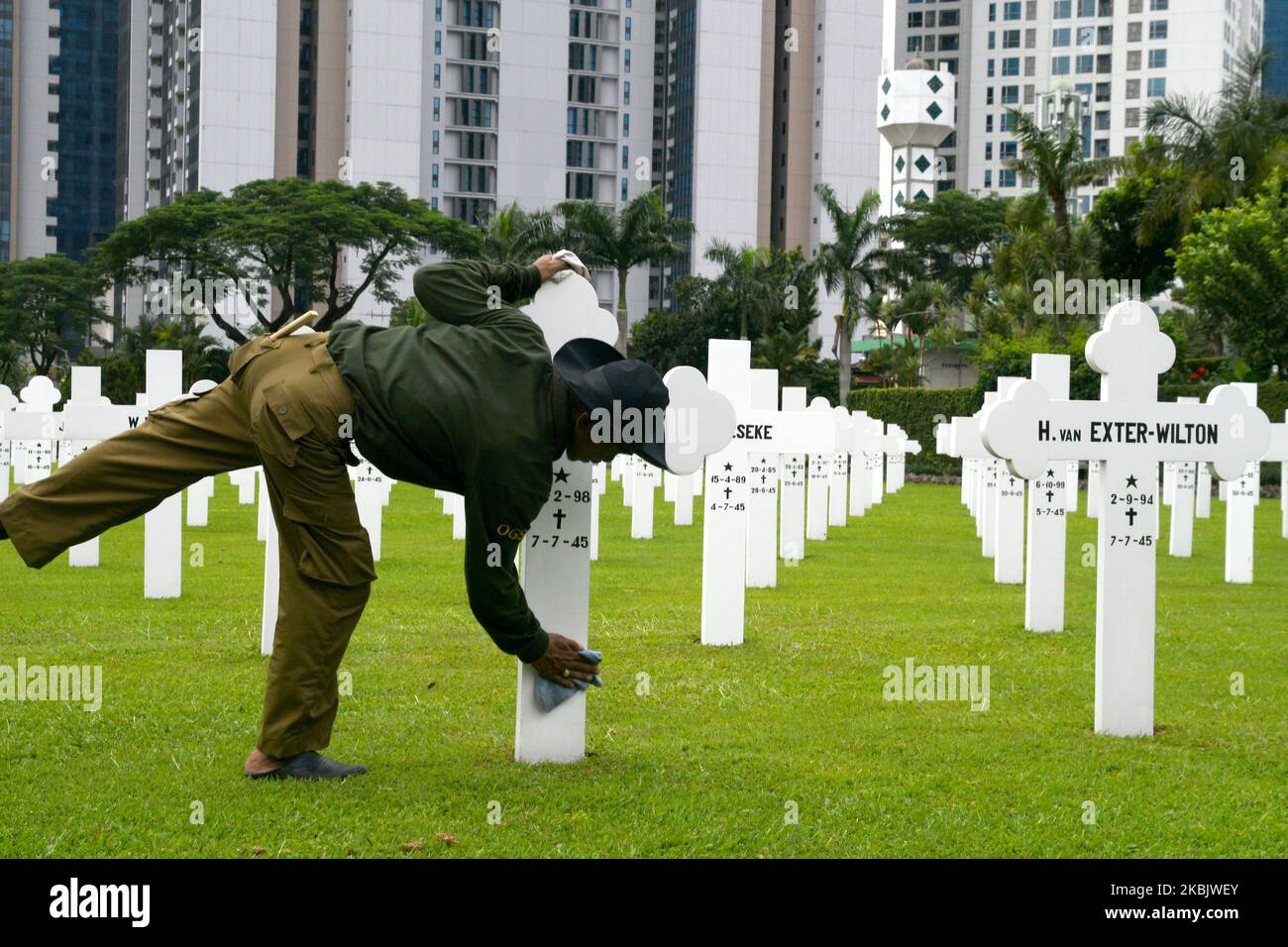 Workers clean gravestone of the Dutch Cemetery soldier in the Ereveld ...