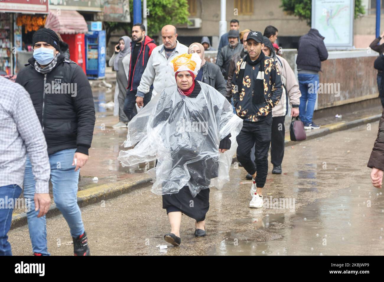 A woman wear plastic bag as he navigates during heavy rains in Cairo ...